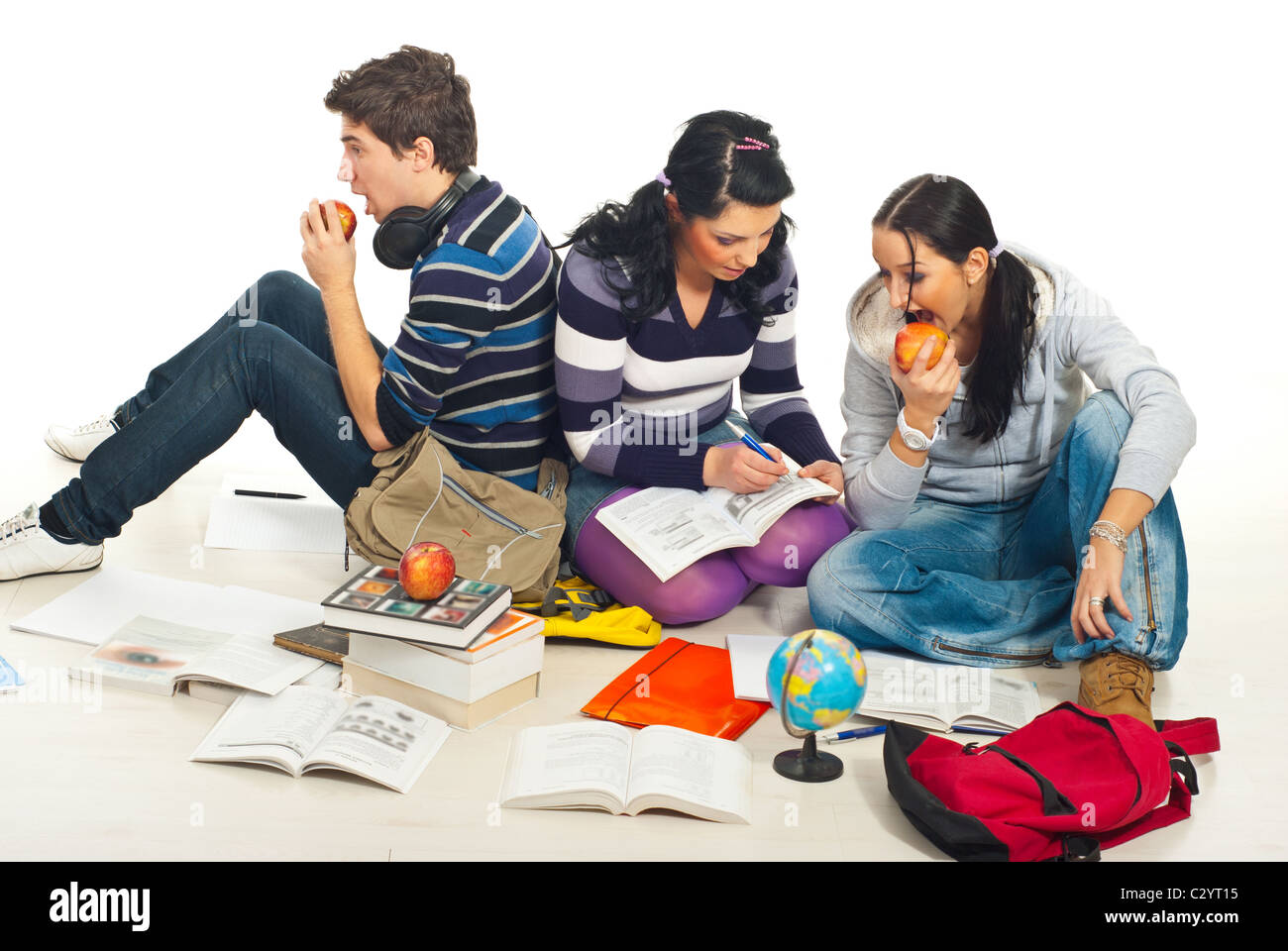Team of three students make homework and eating apples on floor in a ...