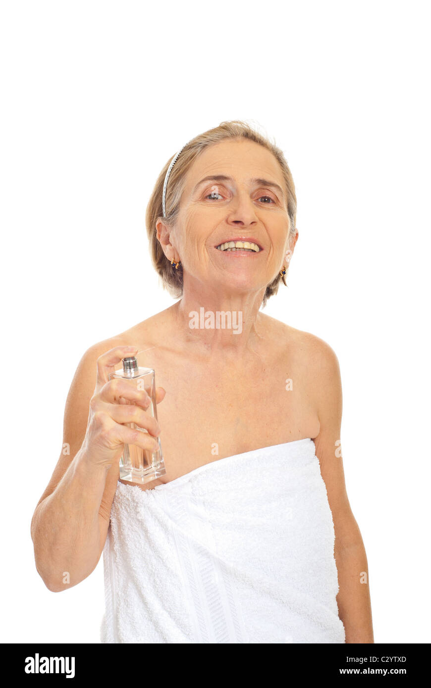 Cheerful senior woman applying perfume on her neck isolated on white ...