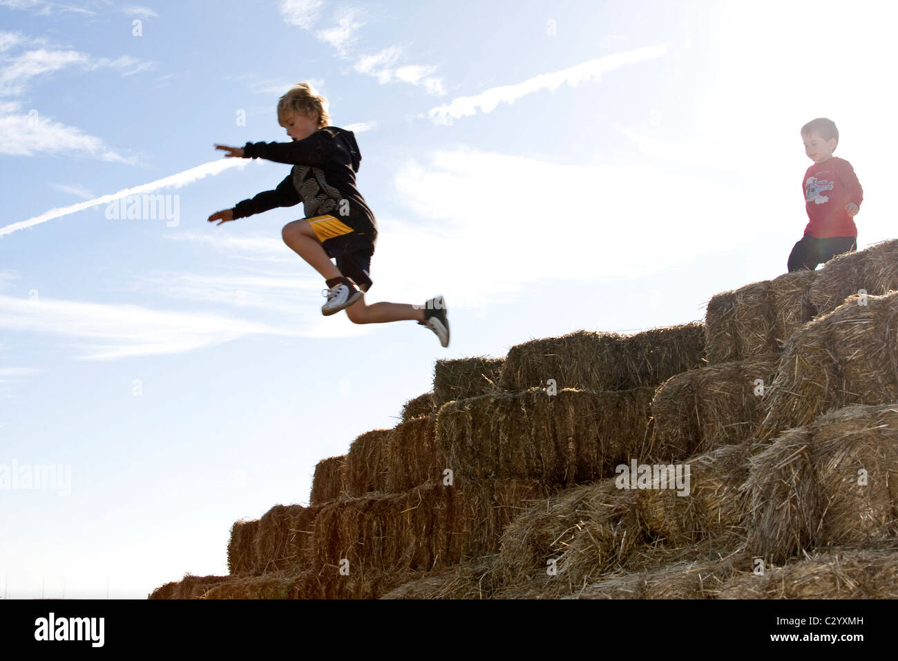 2 brothers jumping off of bales of hay during Halloween Stock Photo - Alamy