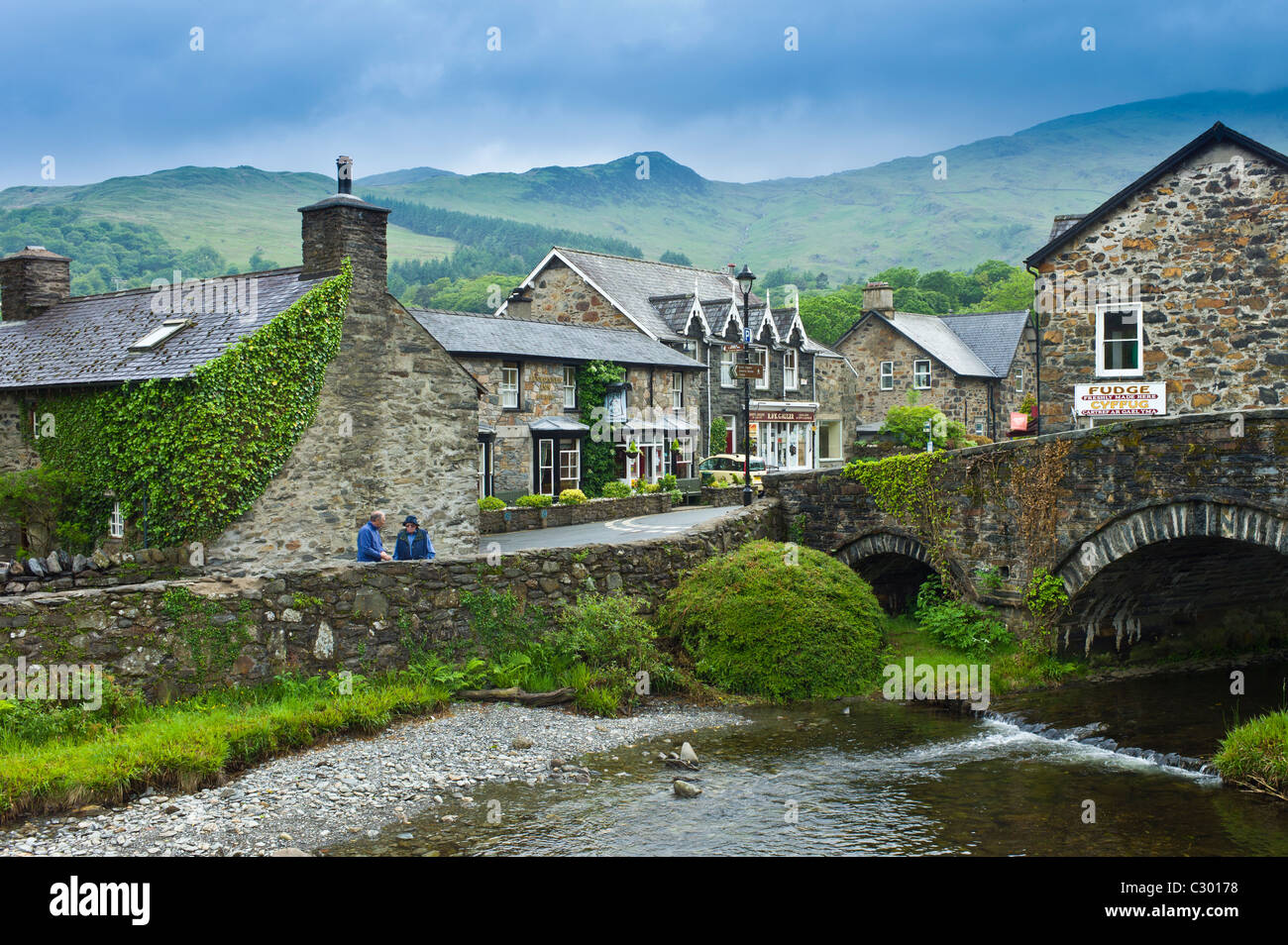 Tourists in village of traditional Welsh stone cottages with Welsh ...