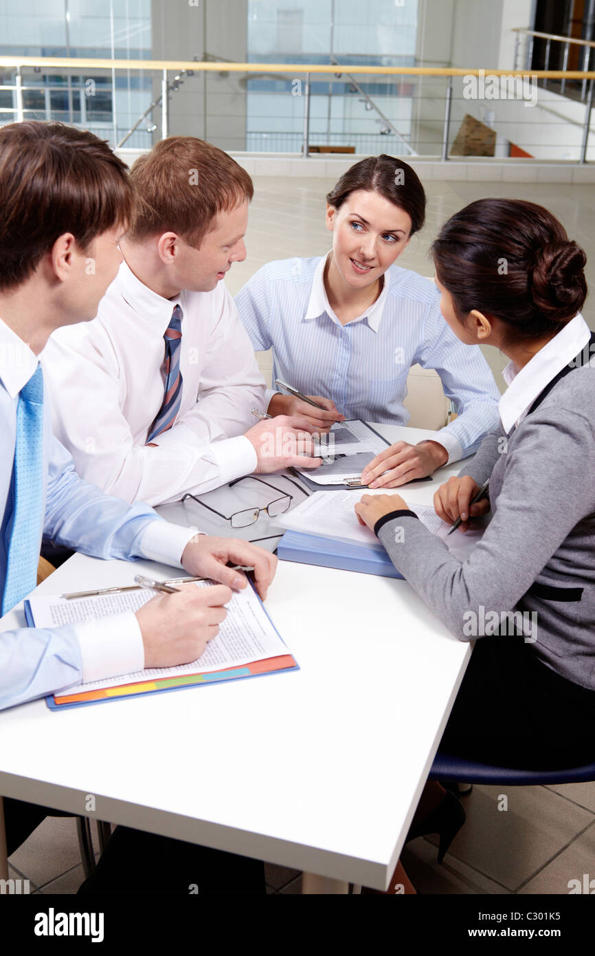 Four business people discussing reports together Stock Photo - Alamy