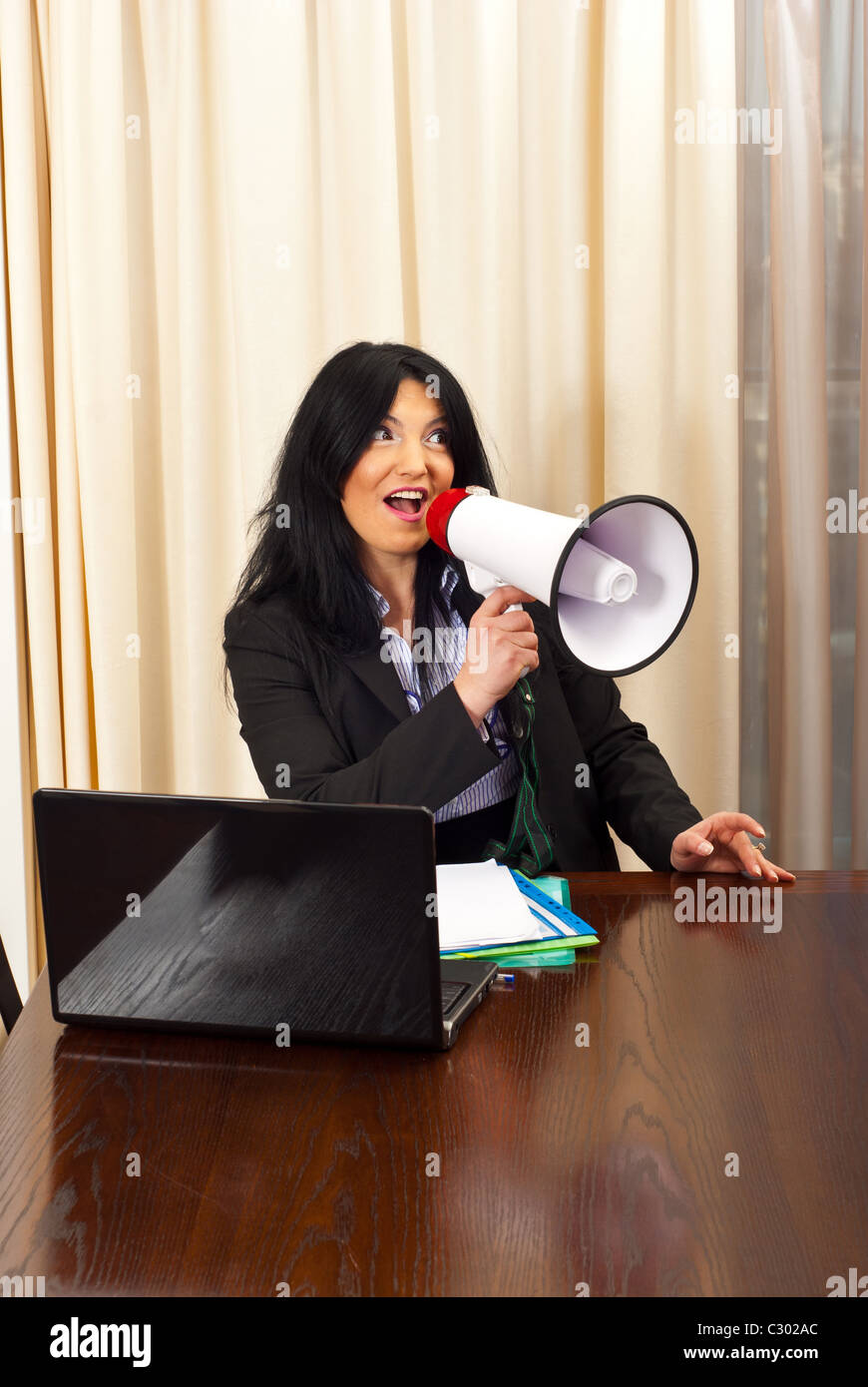 Funny smiling executive woman shouting away in megaphone and sitting on ...