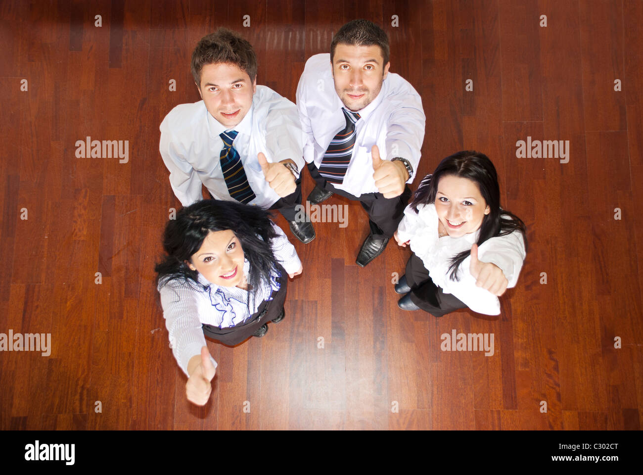 Top view of four business people giving thumbs and looking up Stock ...