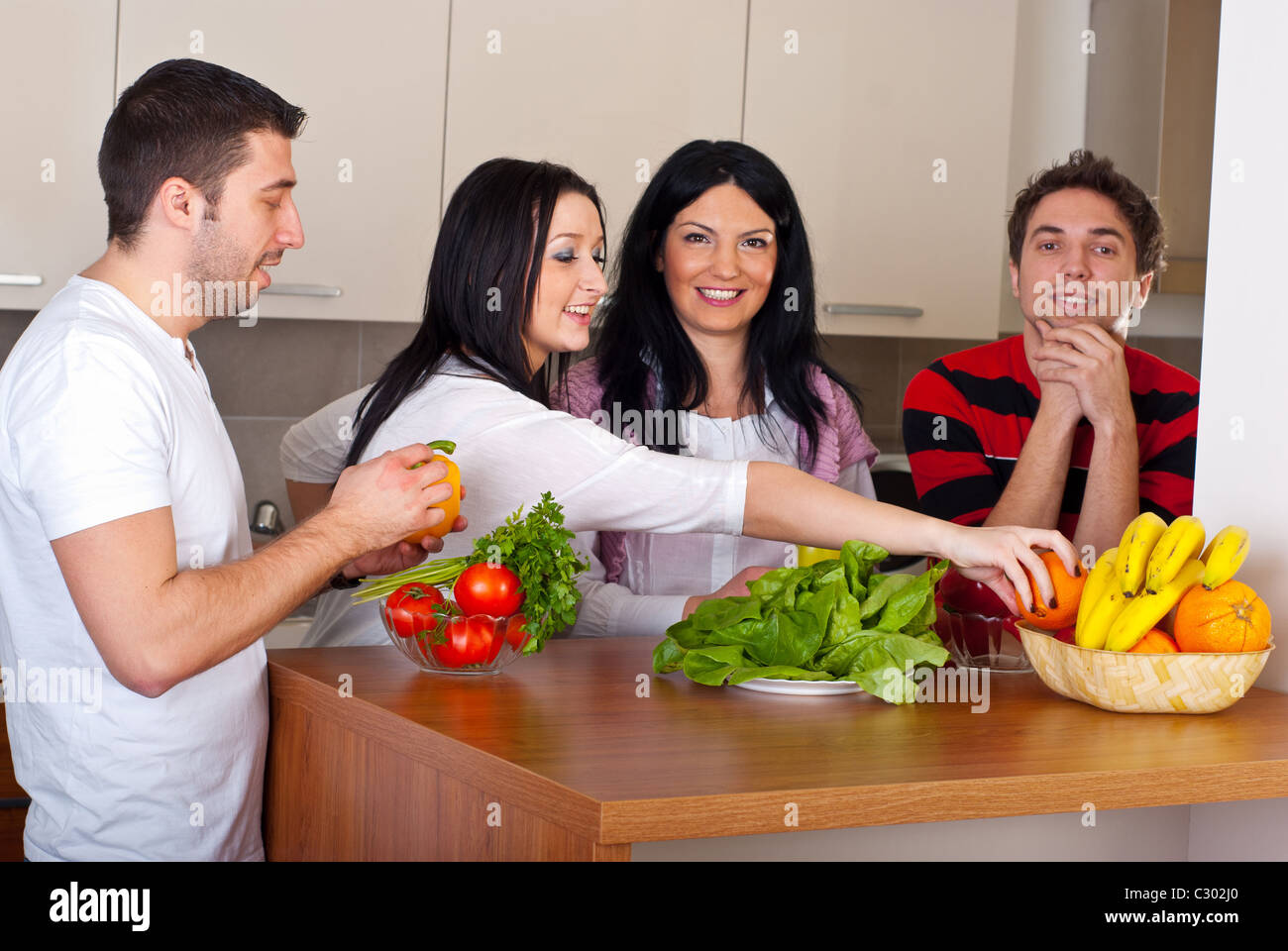 Happy group of friends preparing food with fresh vegetables and having ...