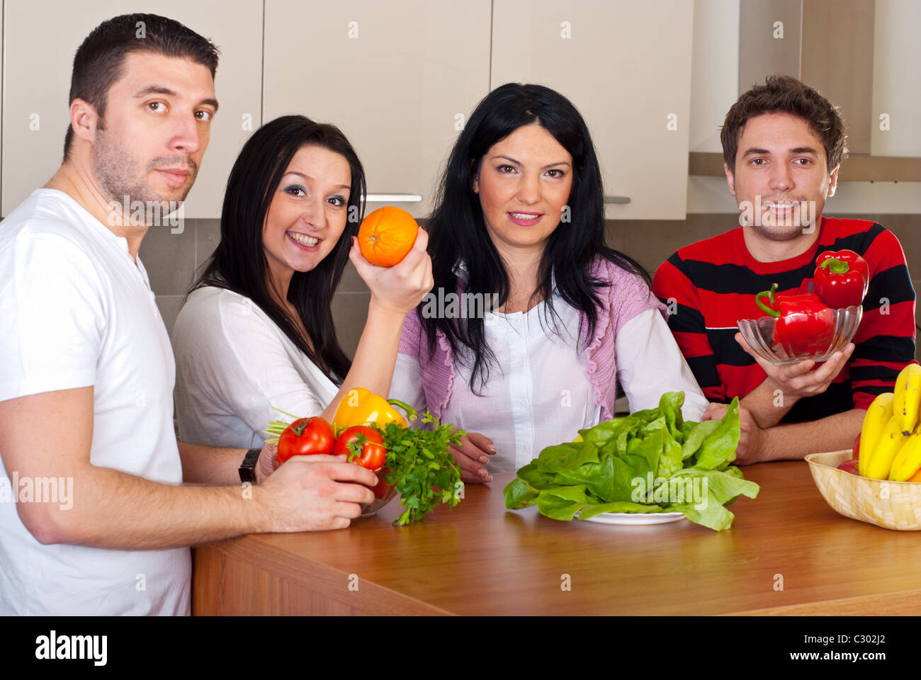 Group of four friends with fruits and vegetables in kitchen Stock Photo ...