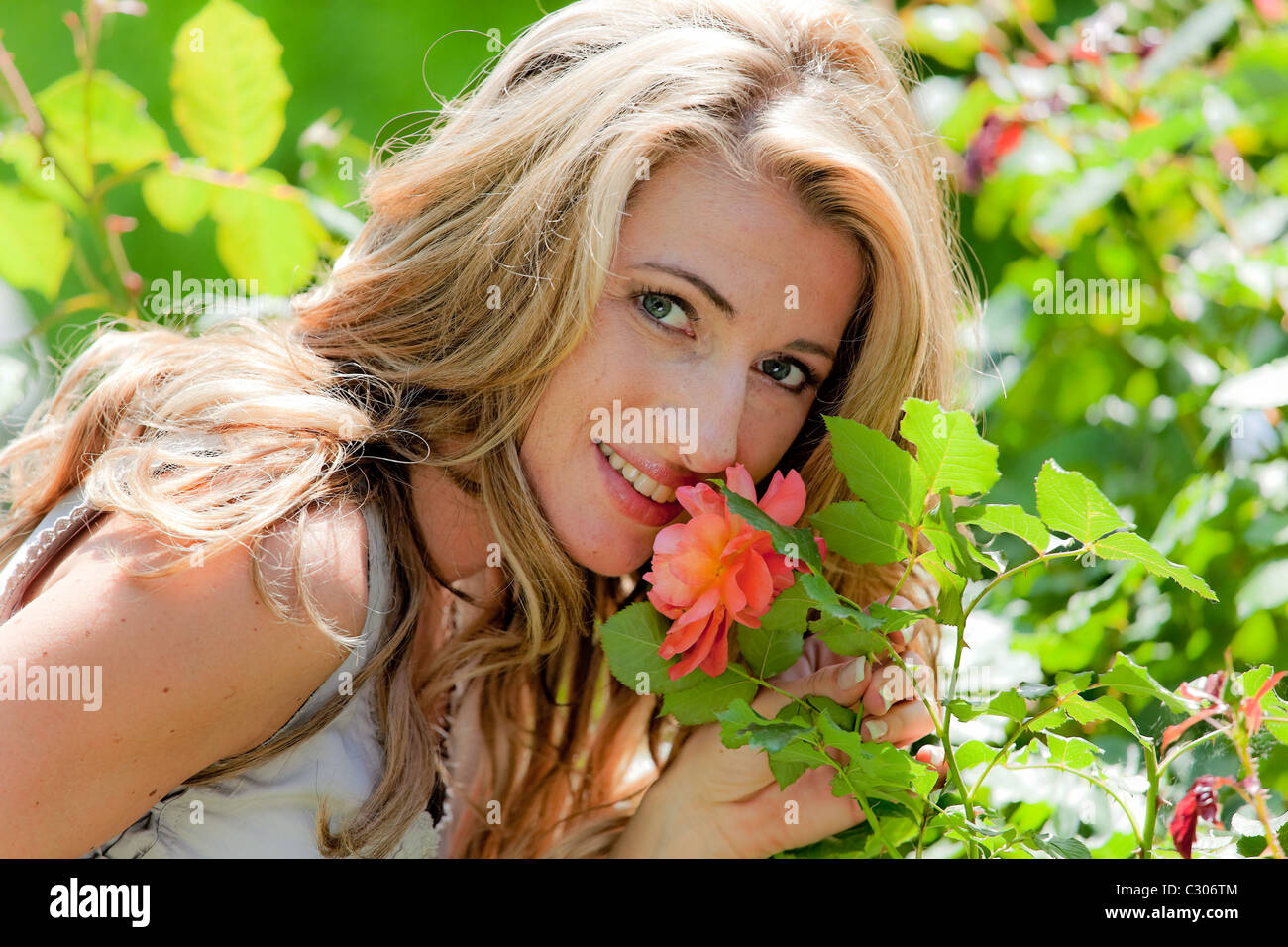 Woman smelling a rose in the garden Stock Photo - Alamy