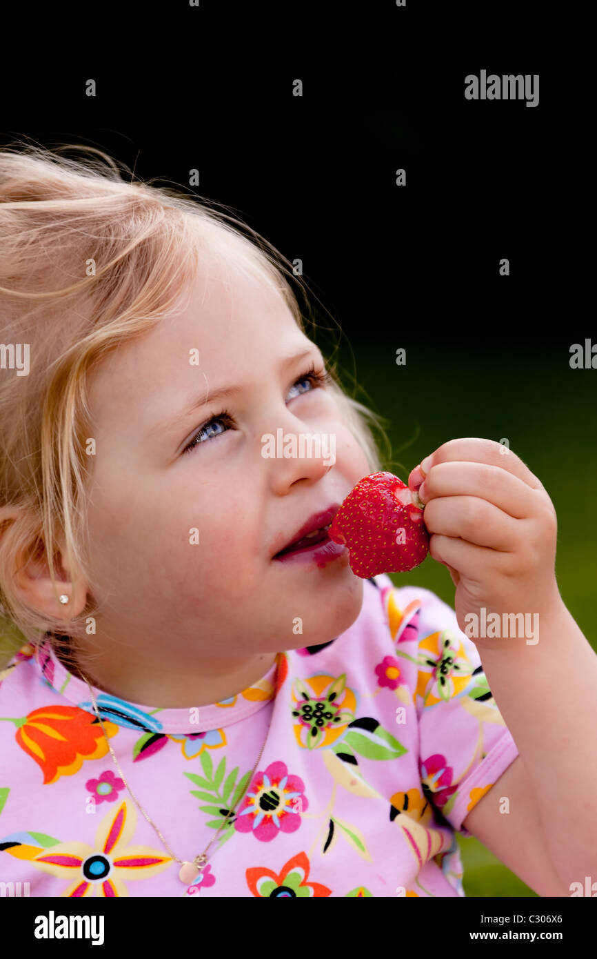 Child eating a strawberry in the garden Stock Photo - Alamy