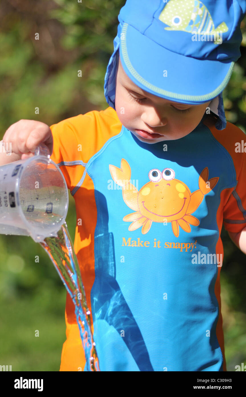 Little 18 months old boy playing with a jug and water Stock Photo - Alamy