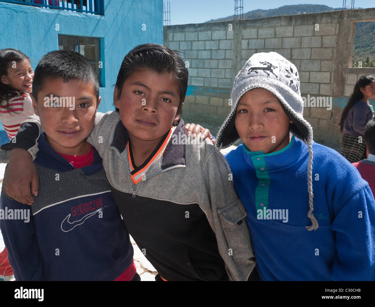 Three young male school children pose for the camera in the schoolyard ...