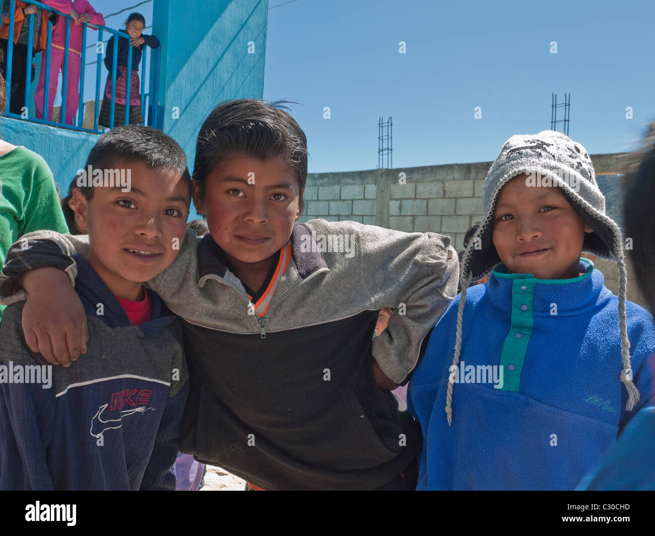 Three young male school children pose for the camera in the schoolyard ...