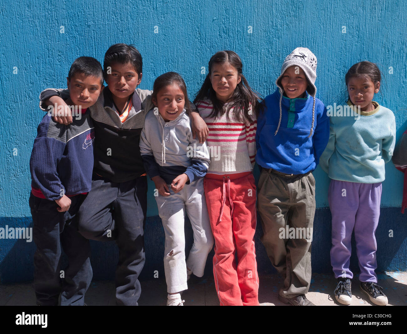 Six primary school students, boys and girls, stand against a bright ...
