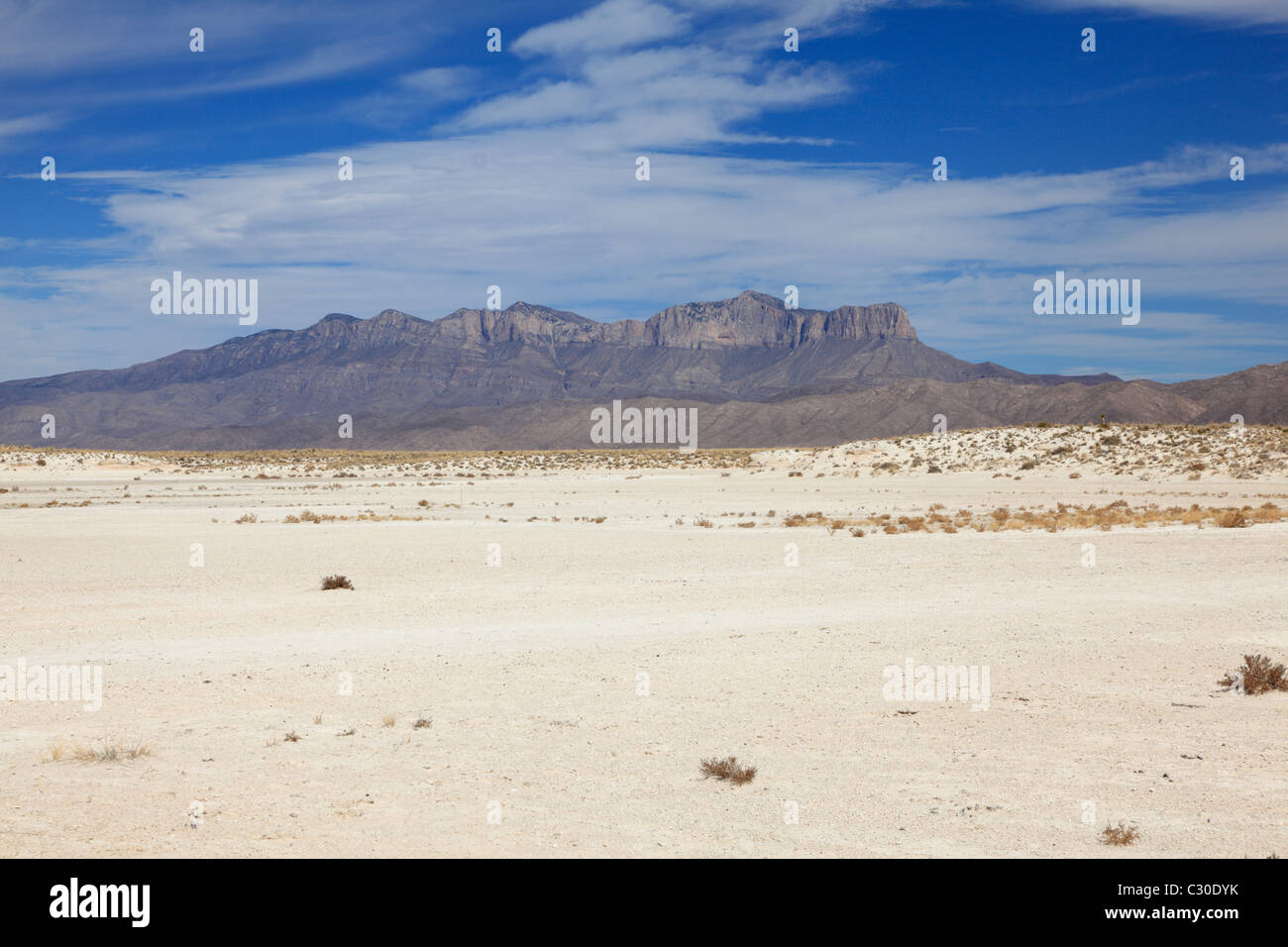 View of the Guadalupe Mountains over gypsum sand. El Capitan peak is ...