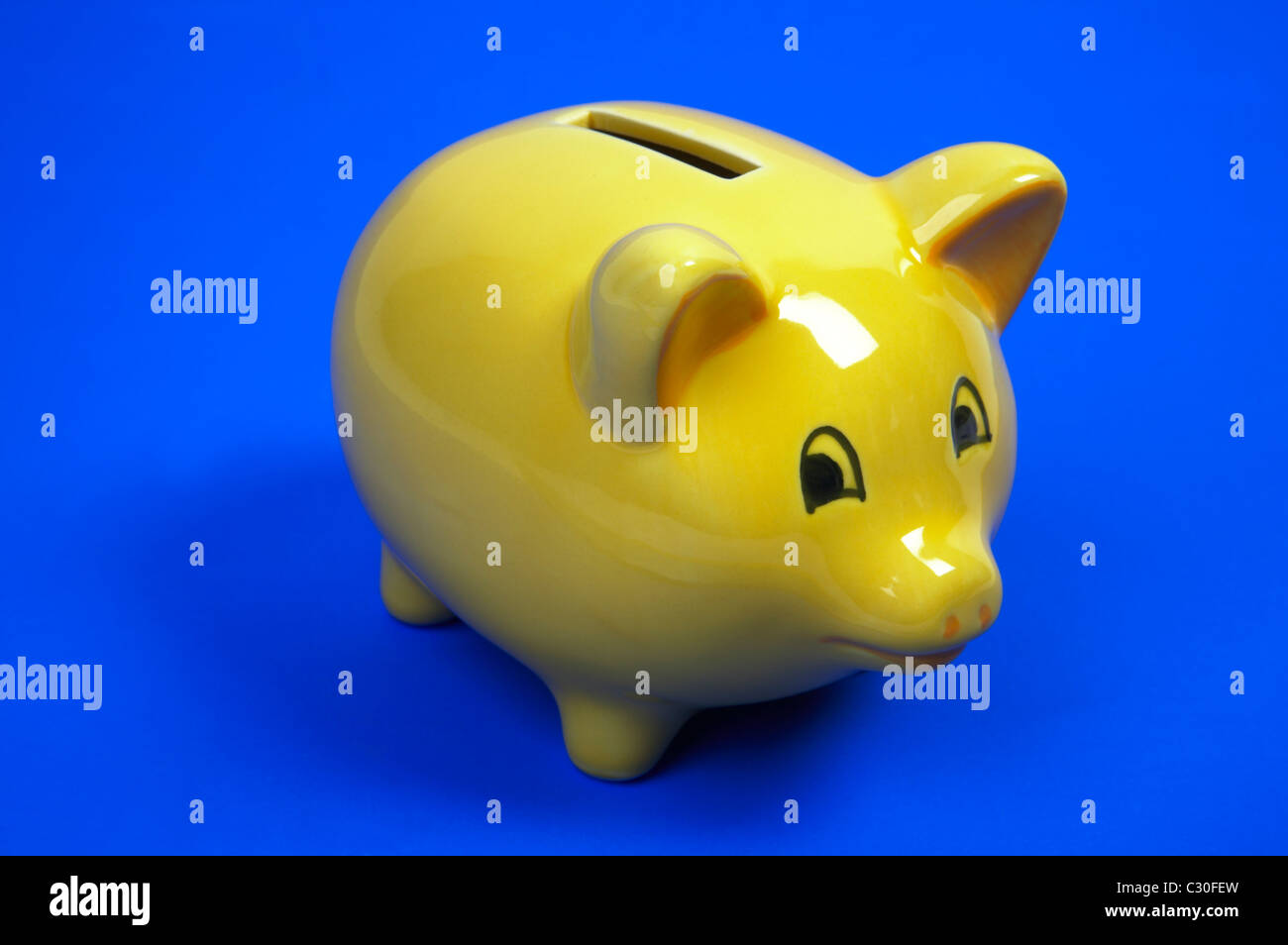 Yellow piggy bank isolated on blue background Stock Photo - Alamy