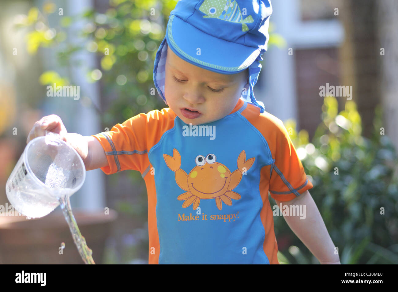 Little 18 months old boy playing with a jug and water Stock Photo - Alamy