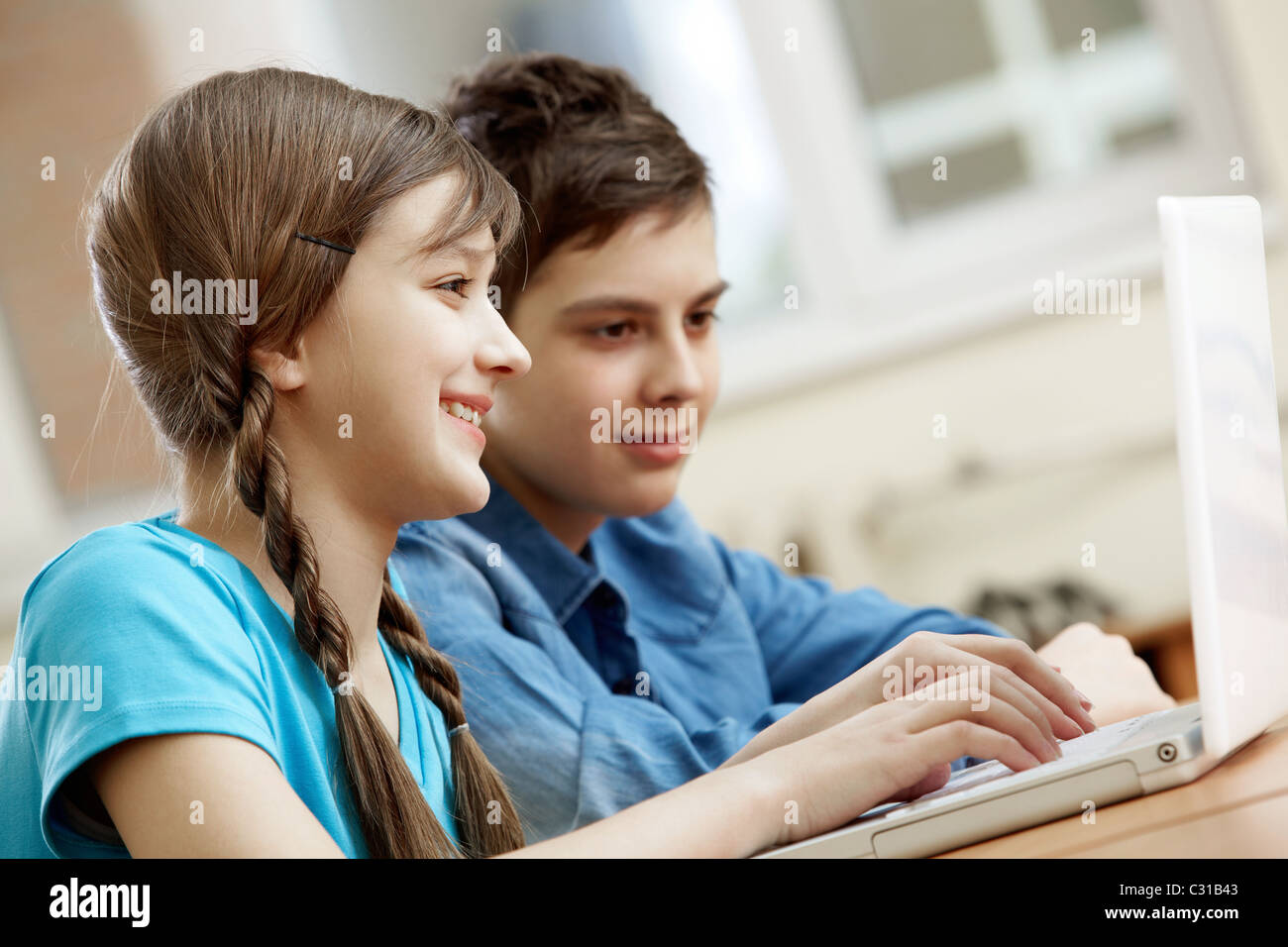 Portrait of teenage girl typing with her classmate at background Stock ...