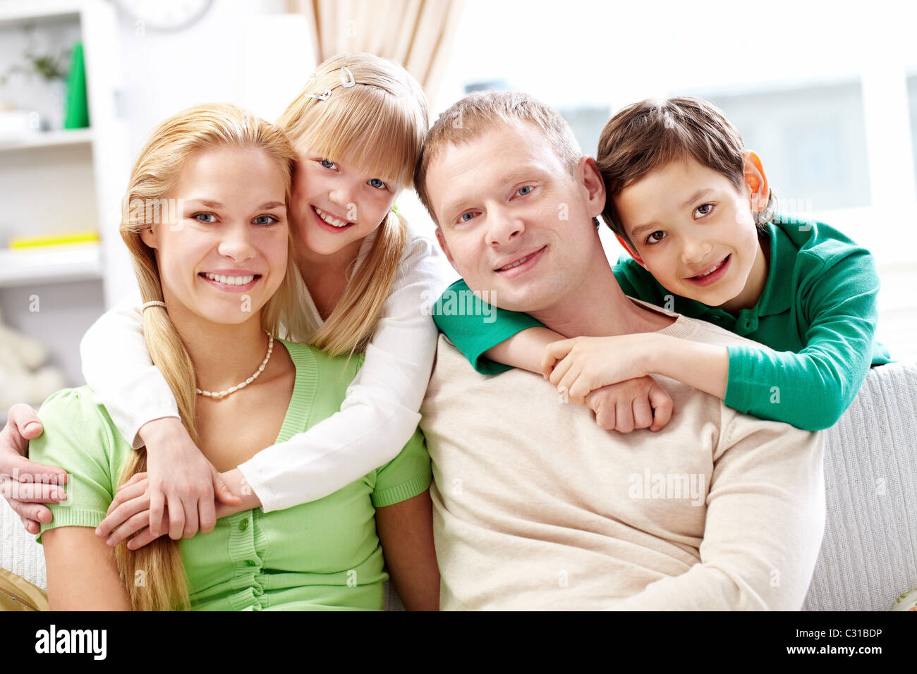 Happy siblings embracing their parents at home Stock Photo - Alamy