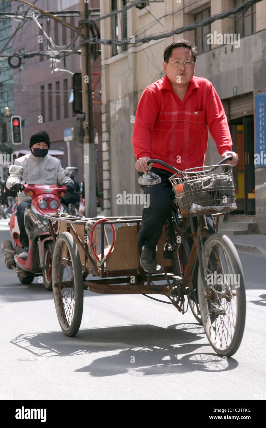 MAN RIDING A TRICYCLE ON A STREET IN THE SHANGHAI CITY CENTER, PUXI ...