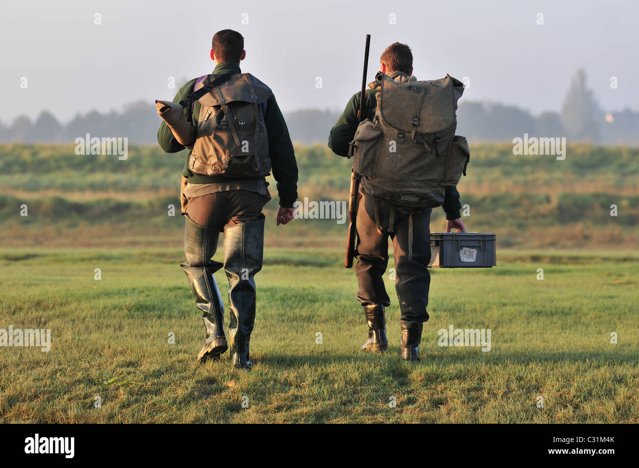 HUNTER WITH HIS GEAR CROSSING A TIDAL POOL COMING BACK FROM THE HUNT ...
