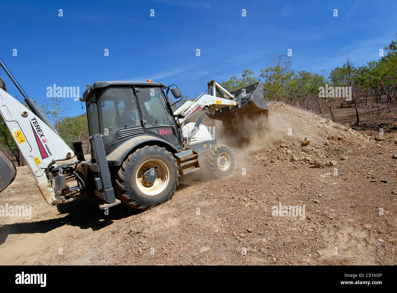 Backhoe depositing soil excavated from a gold mine for subsequent ...
