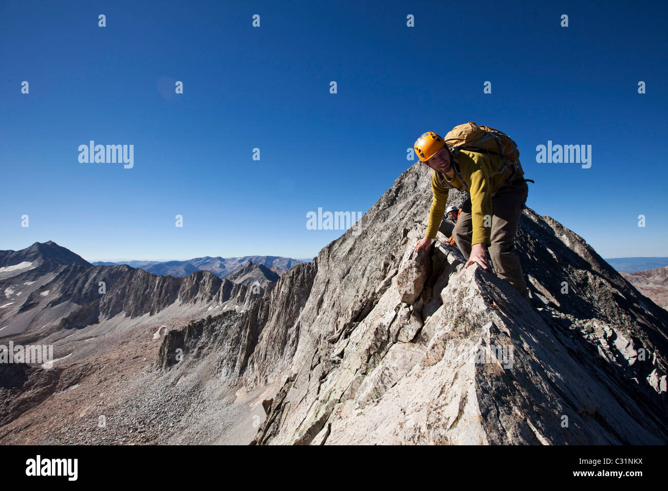Two young men crossing an exposed ridge line with the summit behind ...
