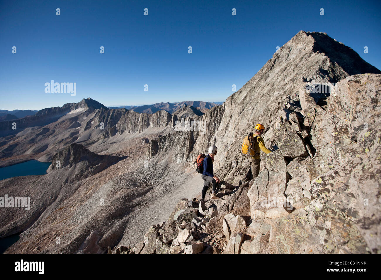 Two young men crossing an exposed ridge line with the summit behind ...