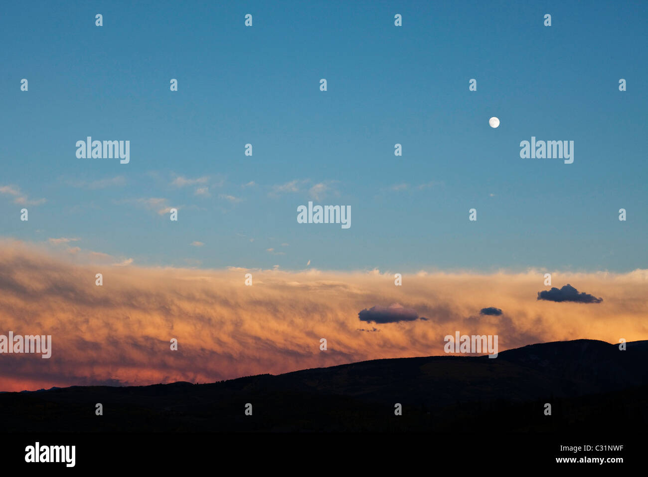 A full moon rises over fiery clouds at sunset Stock Photo - Alamy