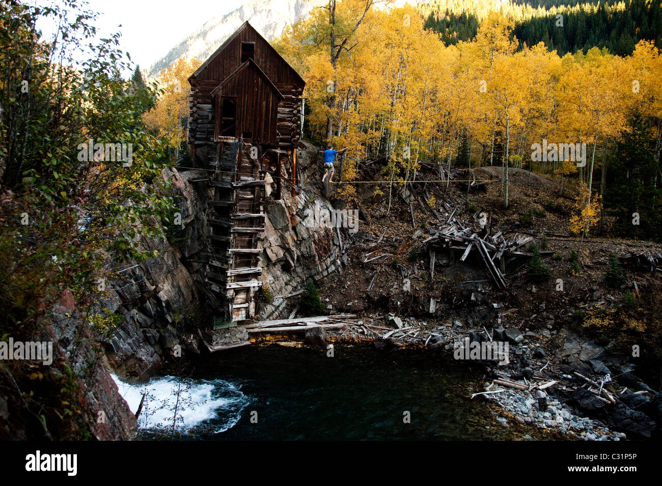 A young man walks a high line with glowing leaves and a raging river ...