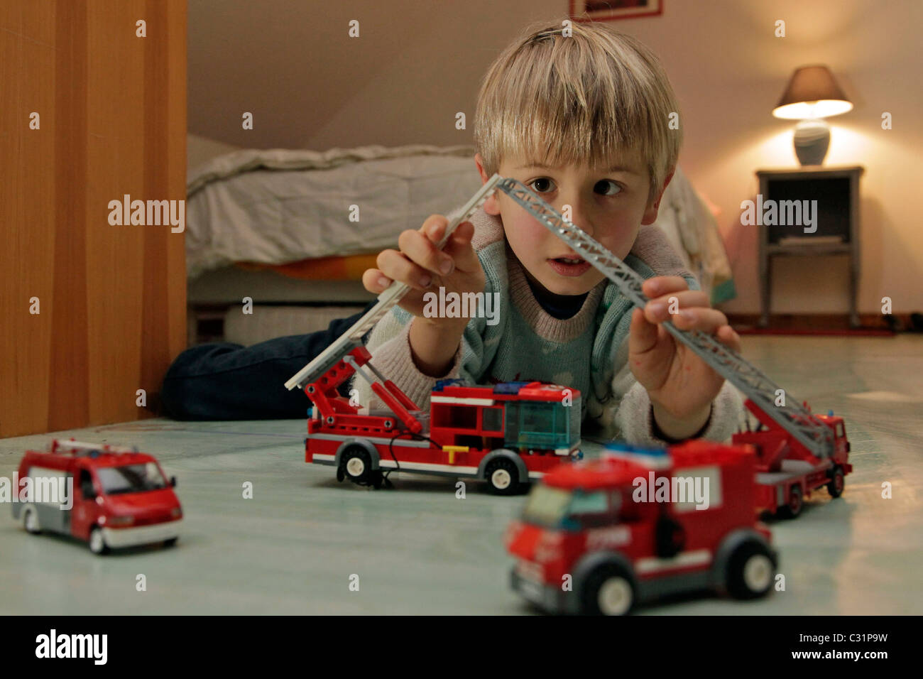 LITTLE BOY PLAYING IN HIS BEDROOM WITH TOY FIRE ENGINES, A PROFESSION ...