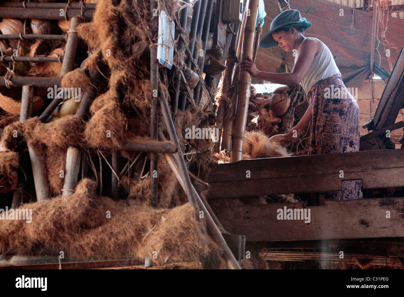 A WOMAN WORKING ON THE PRODUCTION OF THE COCONUT FIBERS USED IN MAKING ...