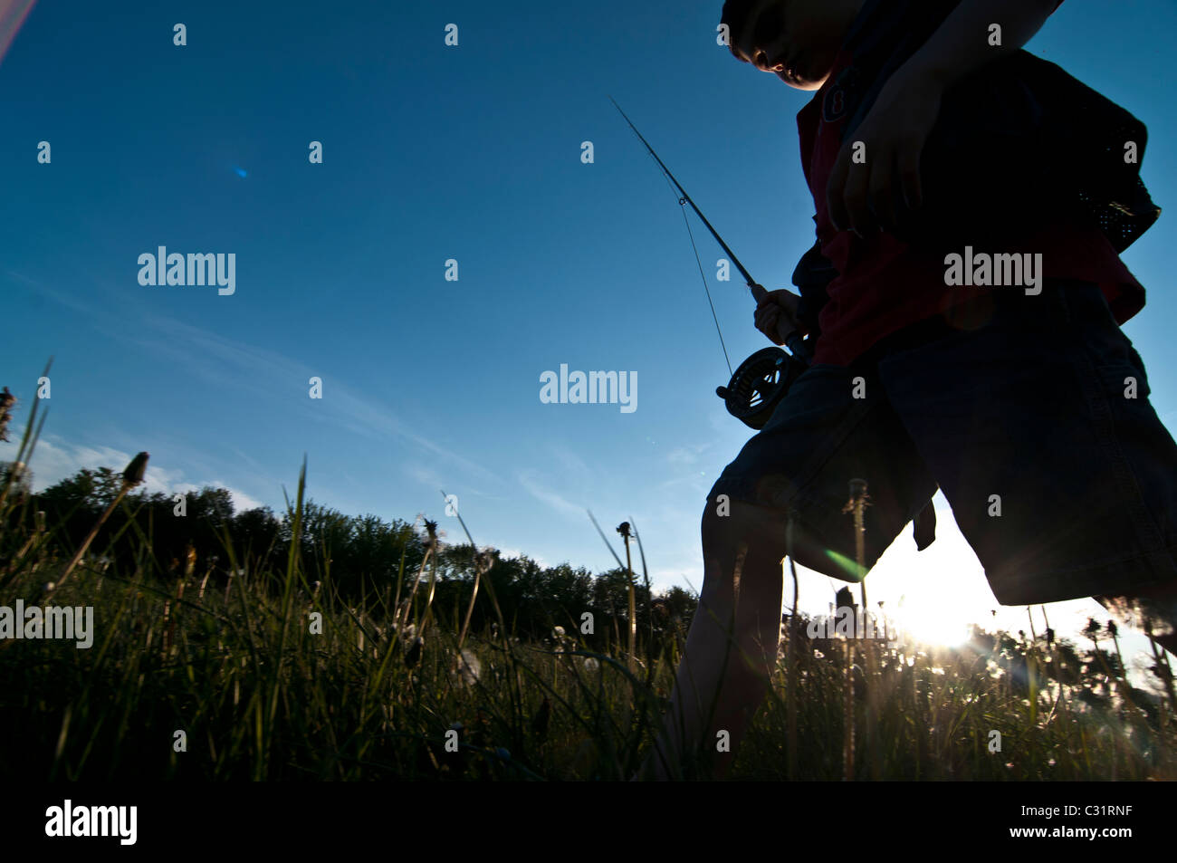 Young boy walking with fly rod Stock Photo - Alamy