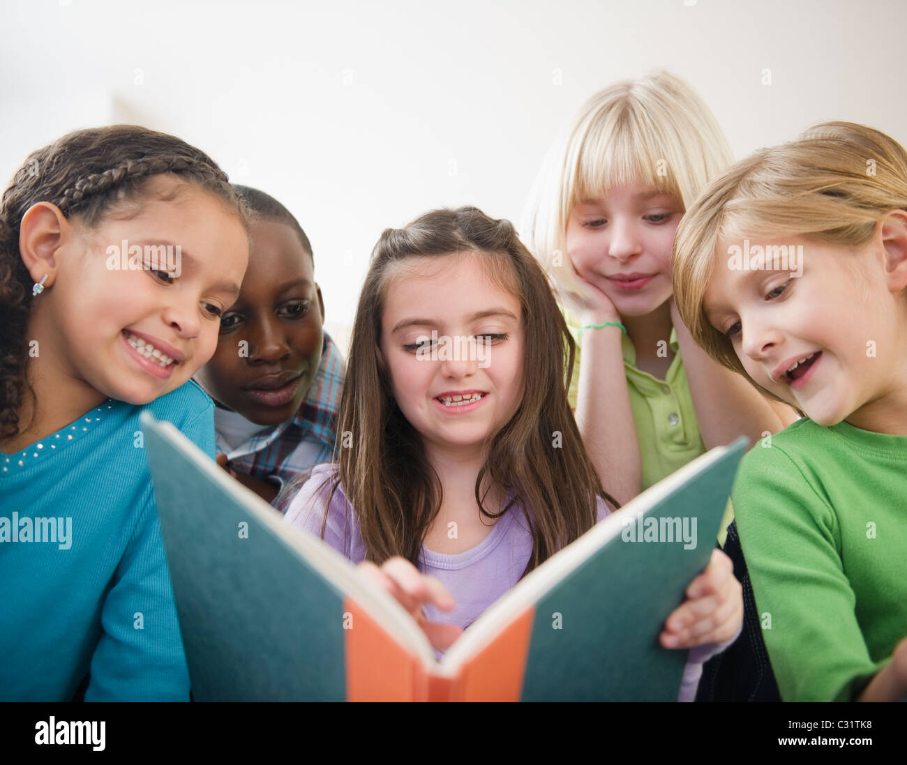 Children reading book together Stock Photo - Alamy