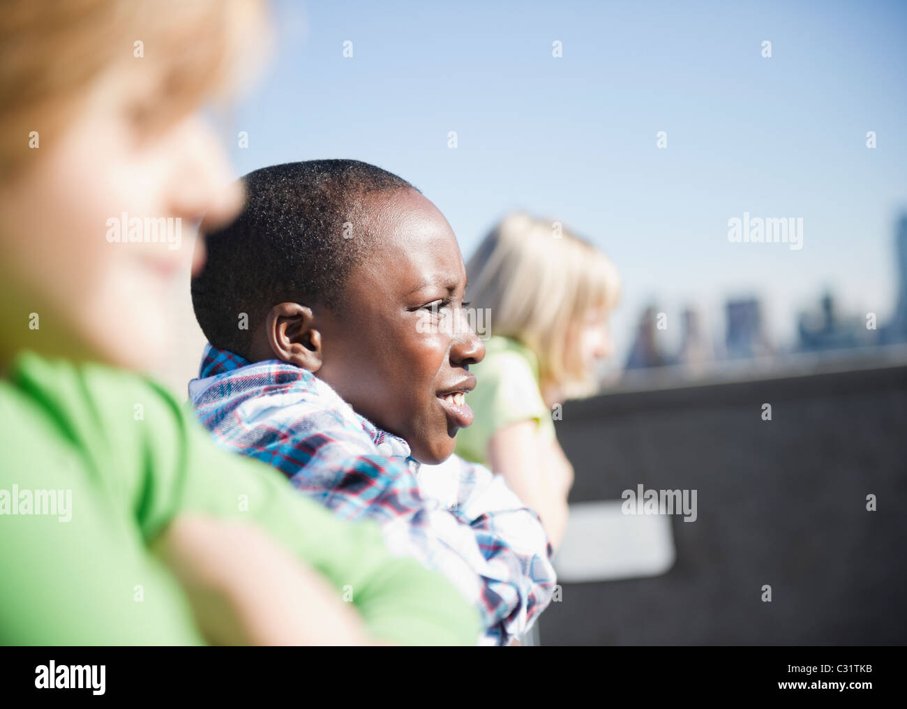 Children looking over rooftop railing Stock Photo - Alamy