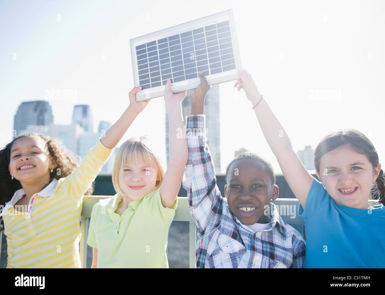 Children on rooftop holding up solar panel Stock Photo - Alamy