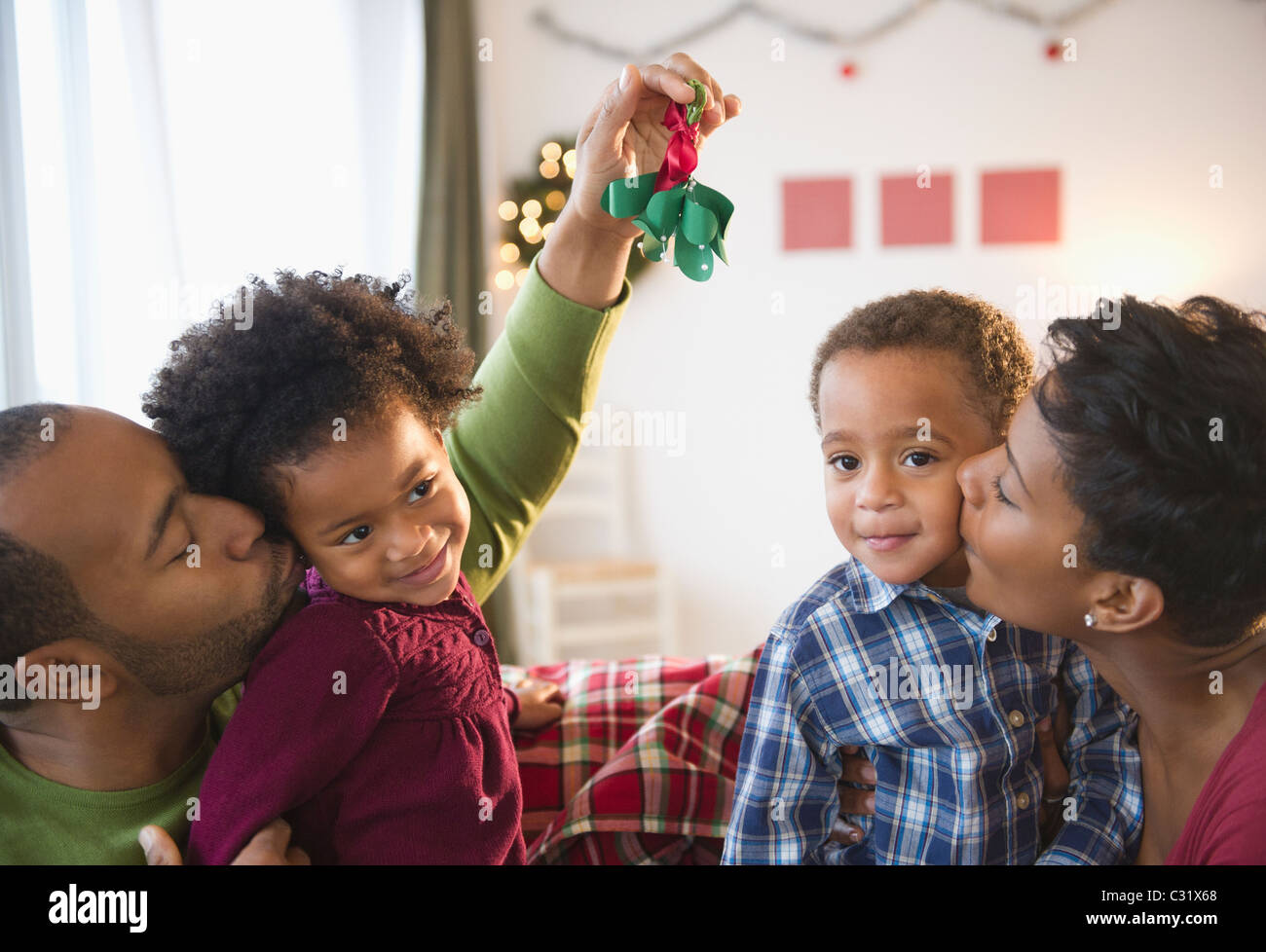 Black father holding mistletoe over daughter's head Stock Photo - Alamy
