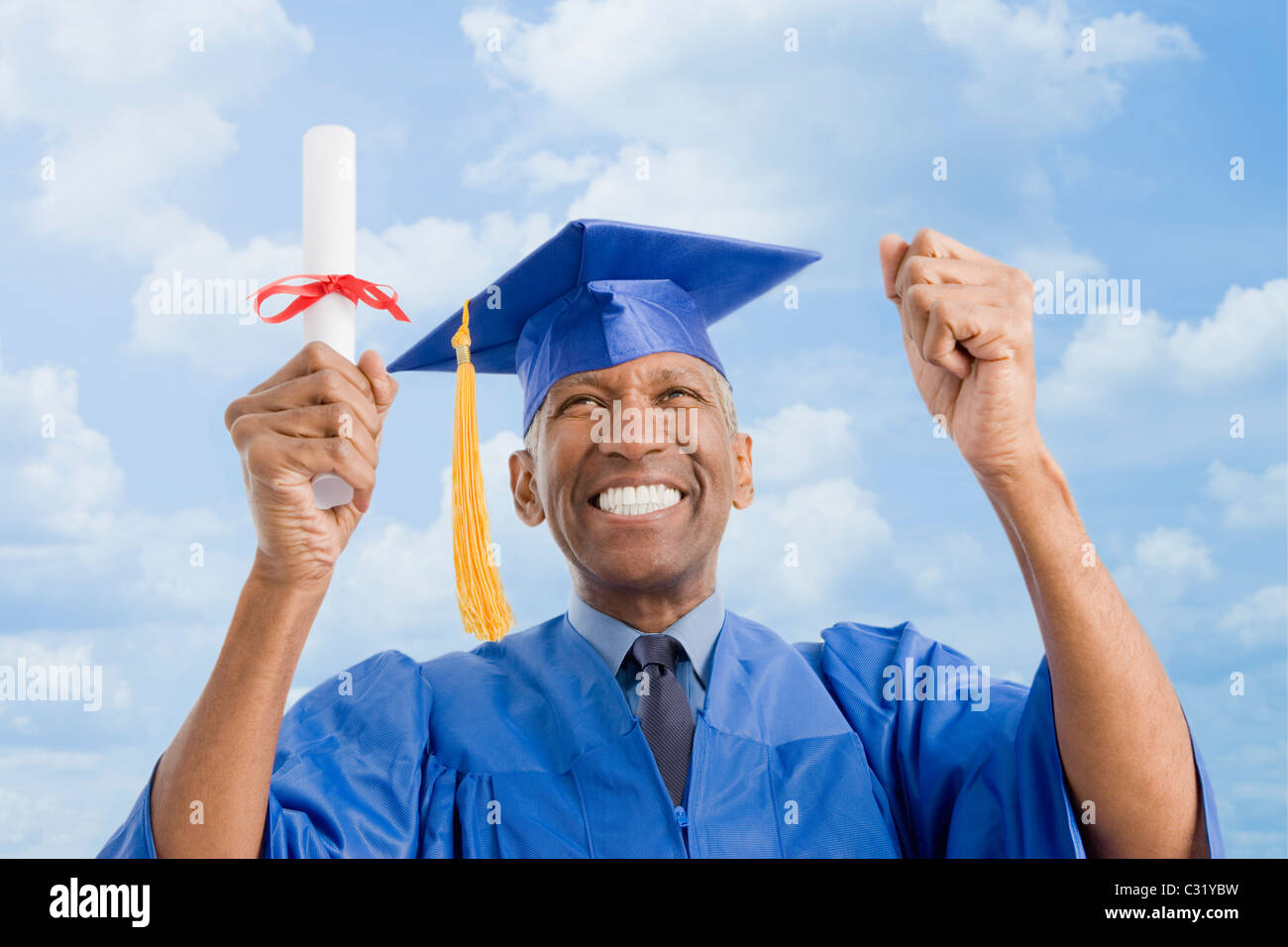 Mixed race man in graduation cap and gown holding diploma Stock Photo ...