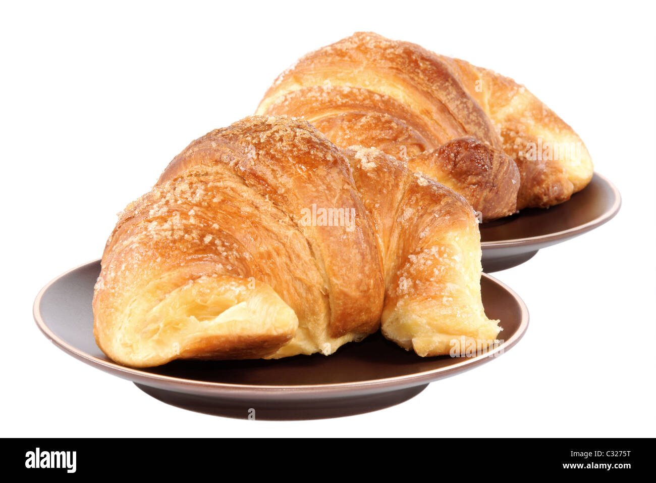 Two croissants served on dark brown ceramic dishes isolated on white ...