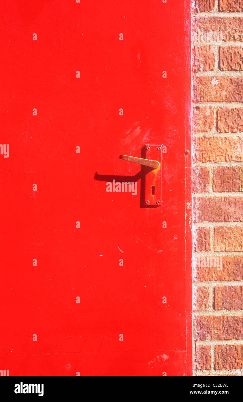 Plain door with handle all painted poppy red with orange brick wall ...