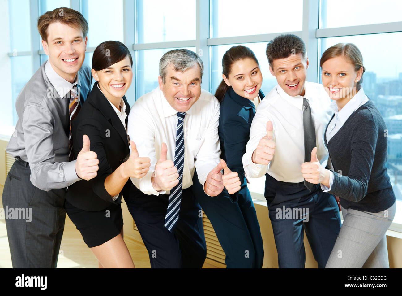 Portrait of happy co-workers looking at camera with smiles and showing ...