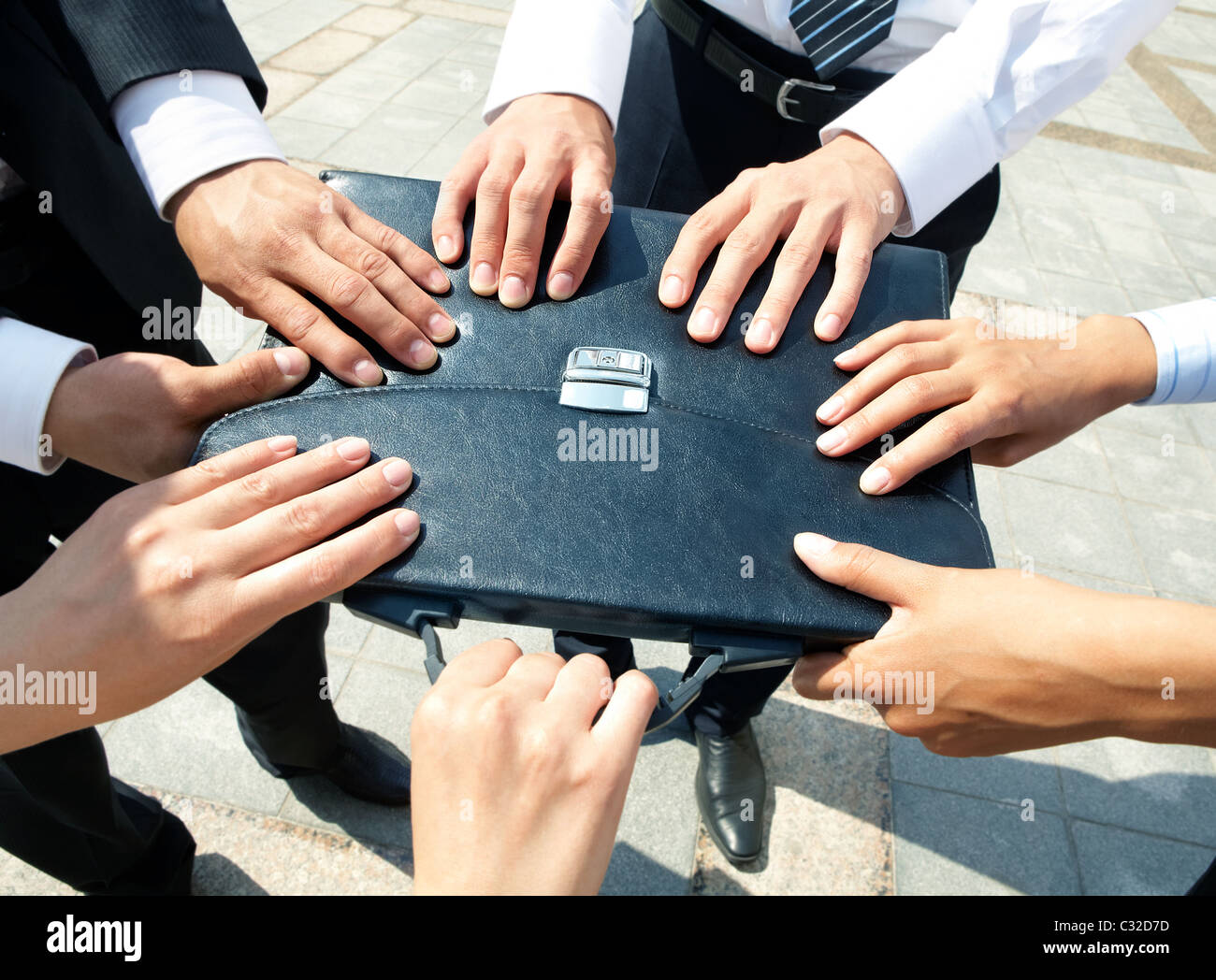 Close-up of people hands holding black leather briefcase simultaneously ...