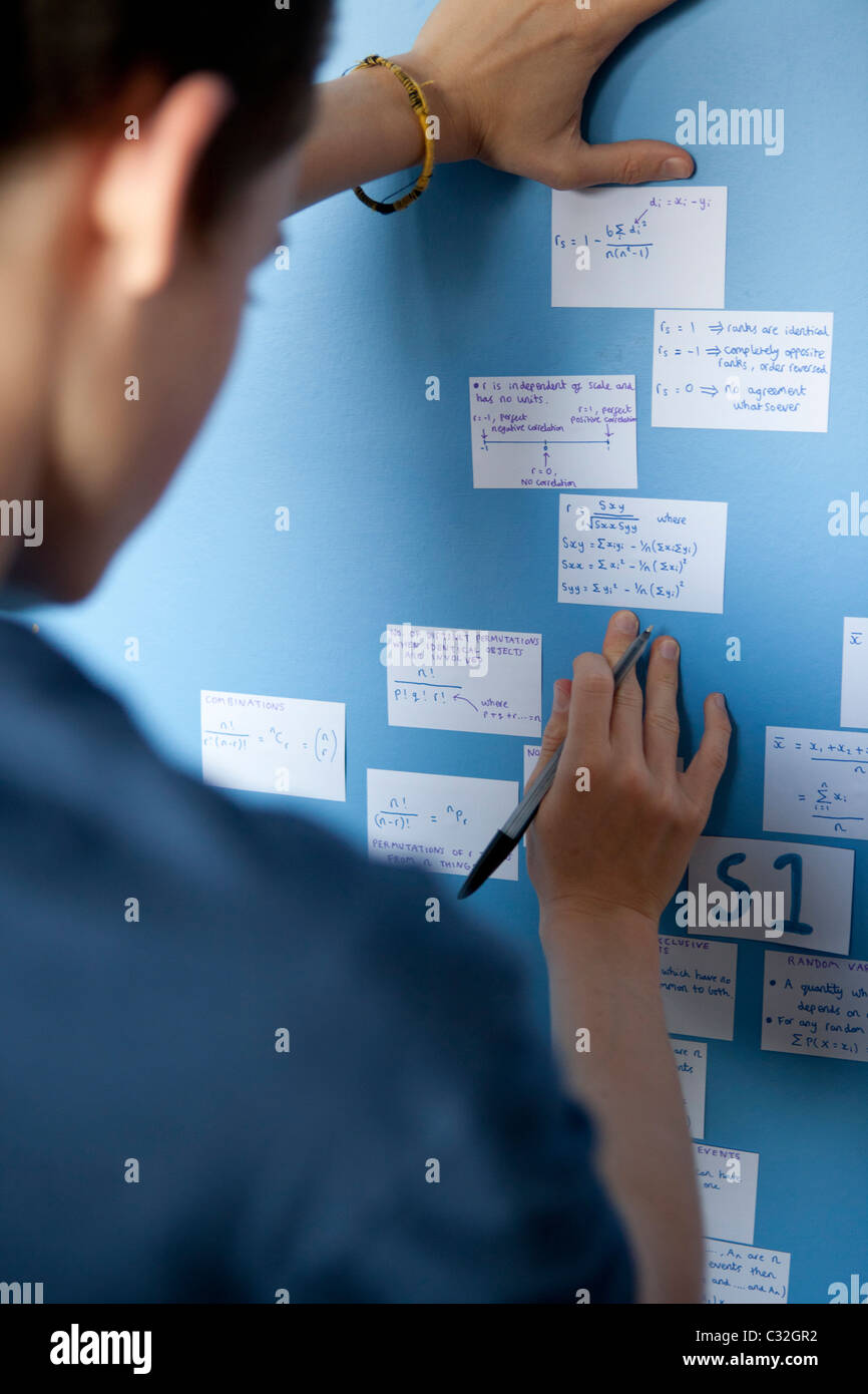 Teenage boy revising for Maths A Level with revision cards stuck on his ...