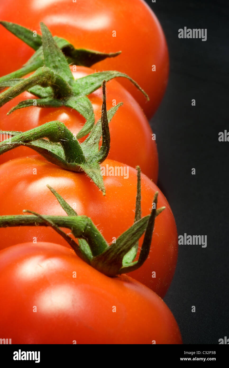 Row of fresh tasty tomatoes on dark background Stock Photo - Alamy