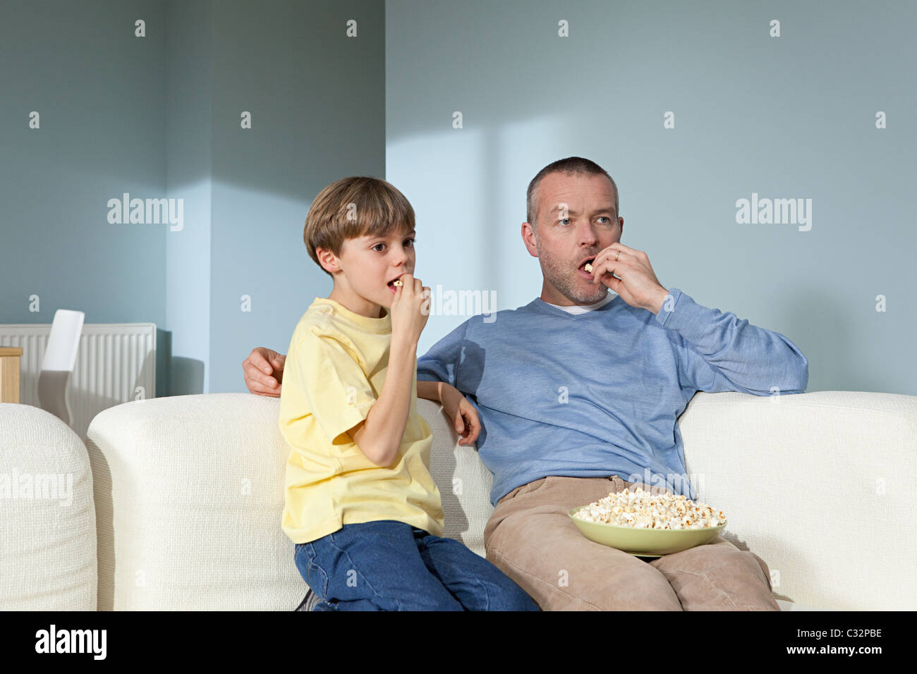 Father and son watching television eating popcorn Stock Photo - Alamy