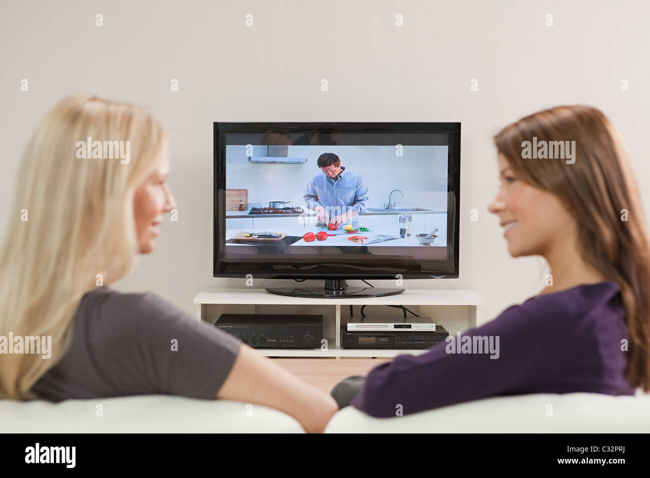 Two young women watching television Stock Photo - Alamy
