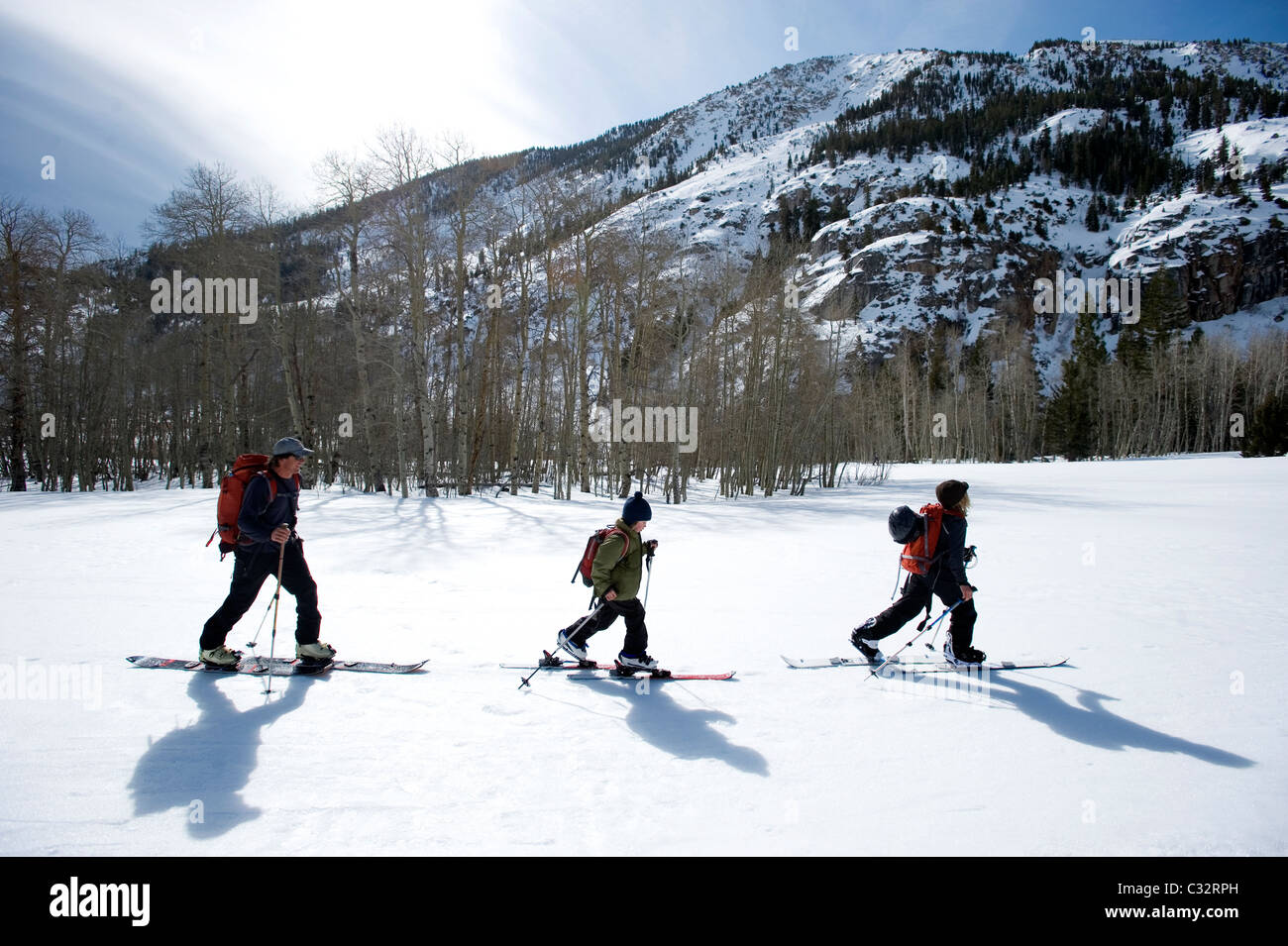 A father and his two sons skinning through the backcountry of ...