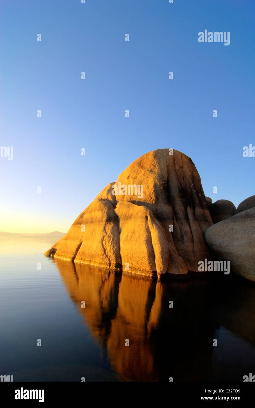 A large granite boulder is illuminated at sunset on the east shore of ...
