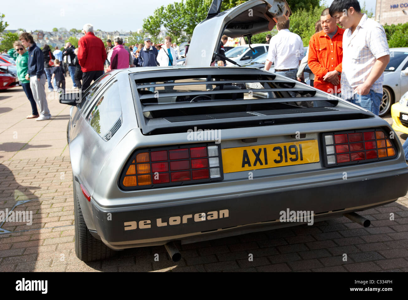 people looking at delorean sports car at a modified car show in ...
