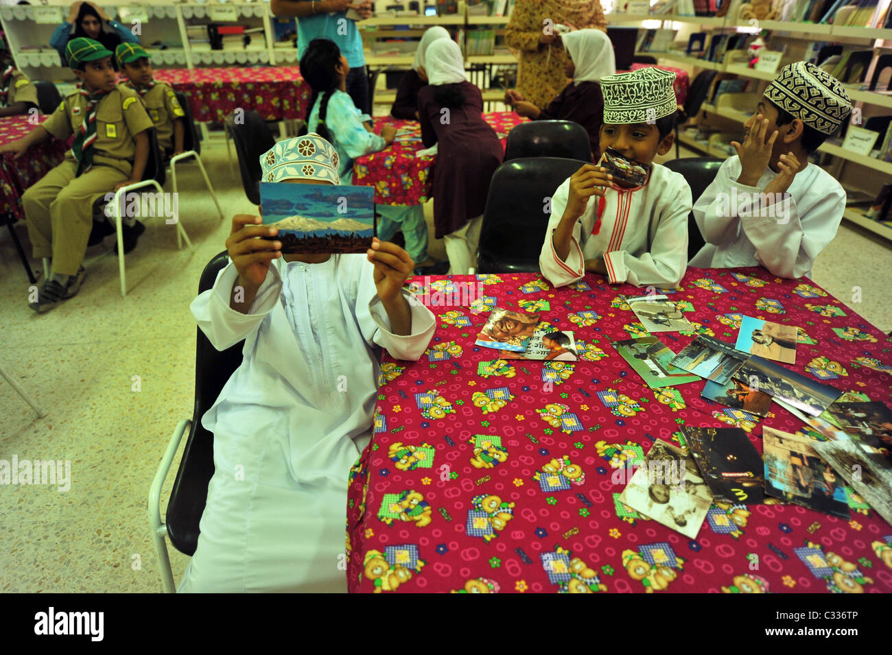 Oman, Muscat, children in traditional dress looking at pictures Stock ...