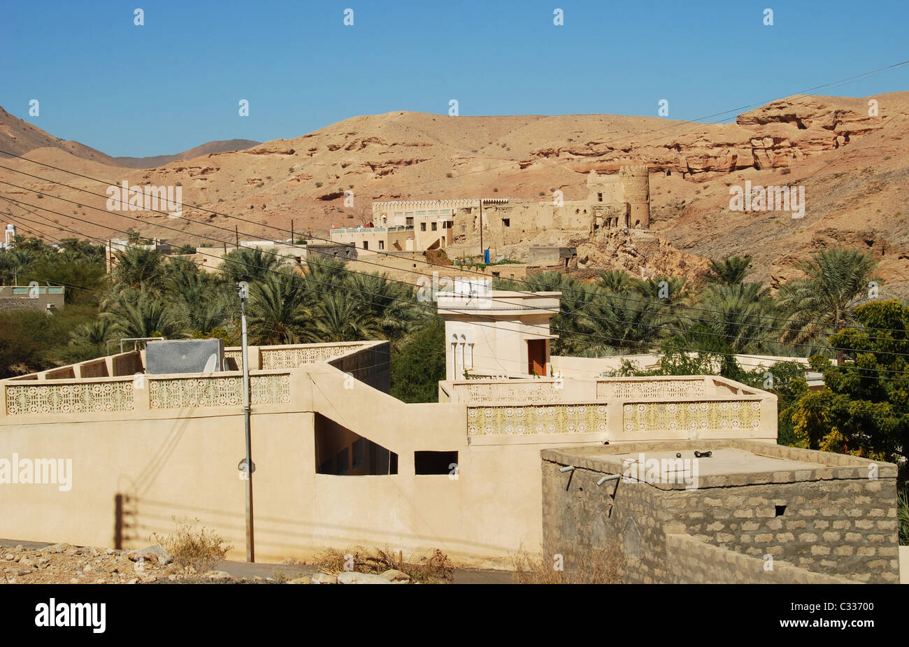 Oman, Al Mazarah, house surrounded with palm trees and mountains in the ...