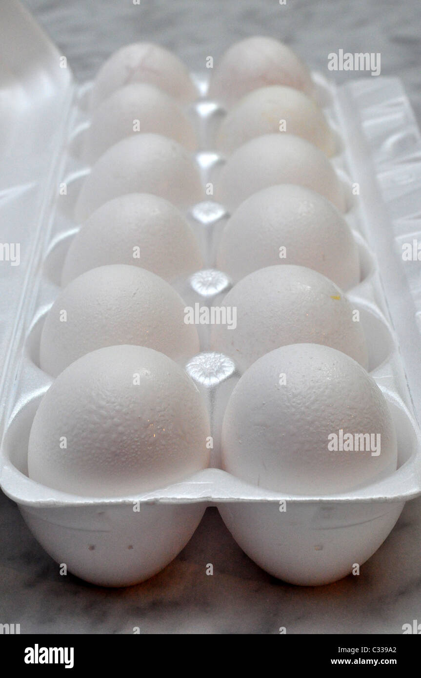A dozen eggs in a white cartoon on a off white background Stock Photo ...