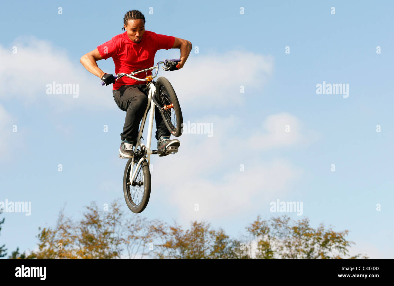Urban sport stunt boy young man teen jumping against blue sky doing ...